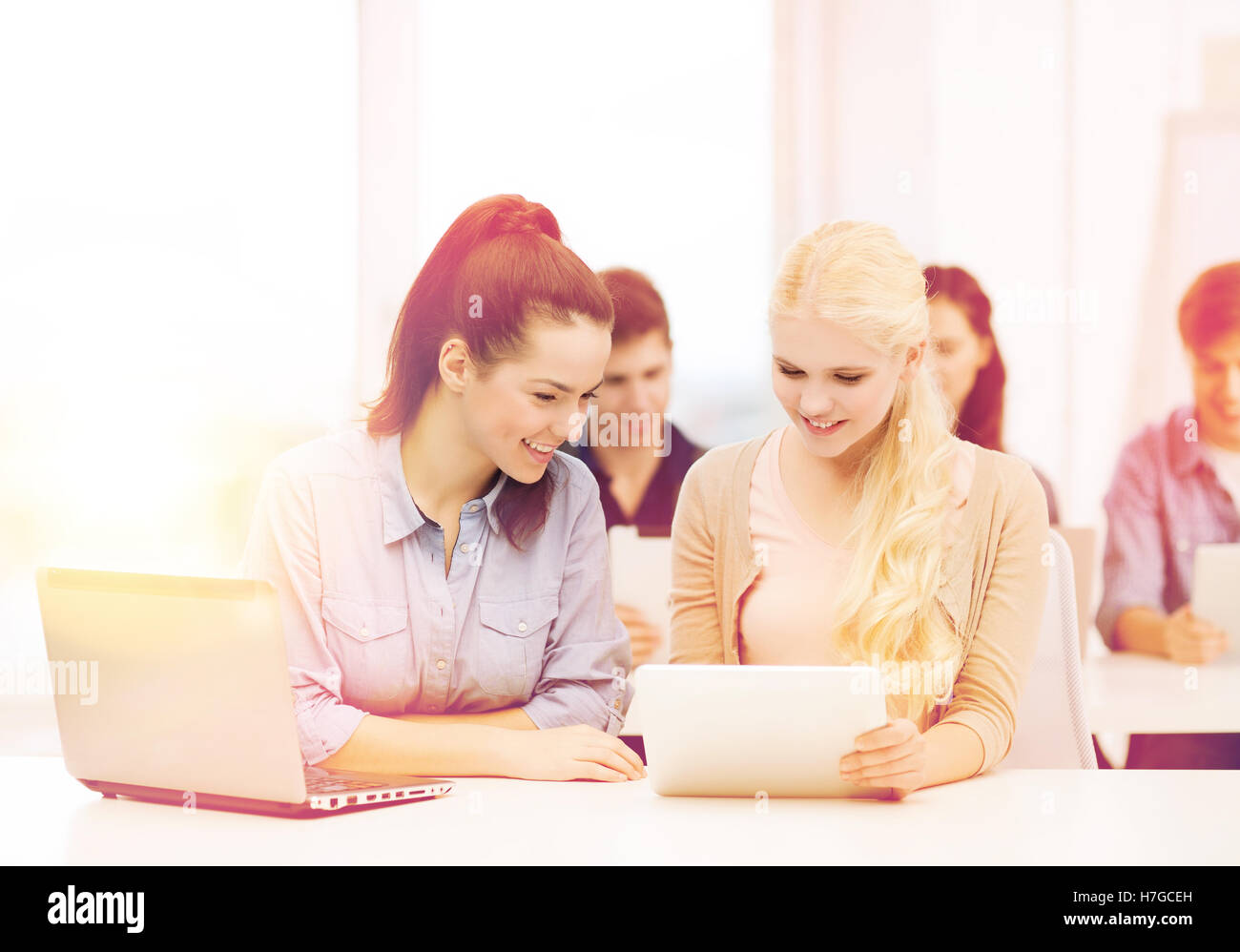 two smiling students with laptop and tablet pc Stock Photo - Alamy