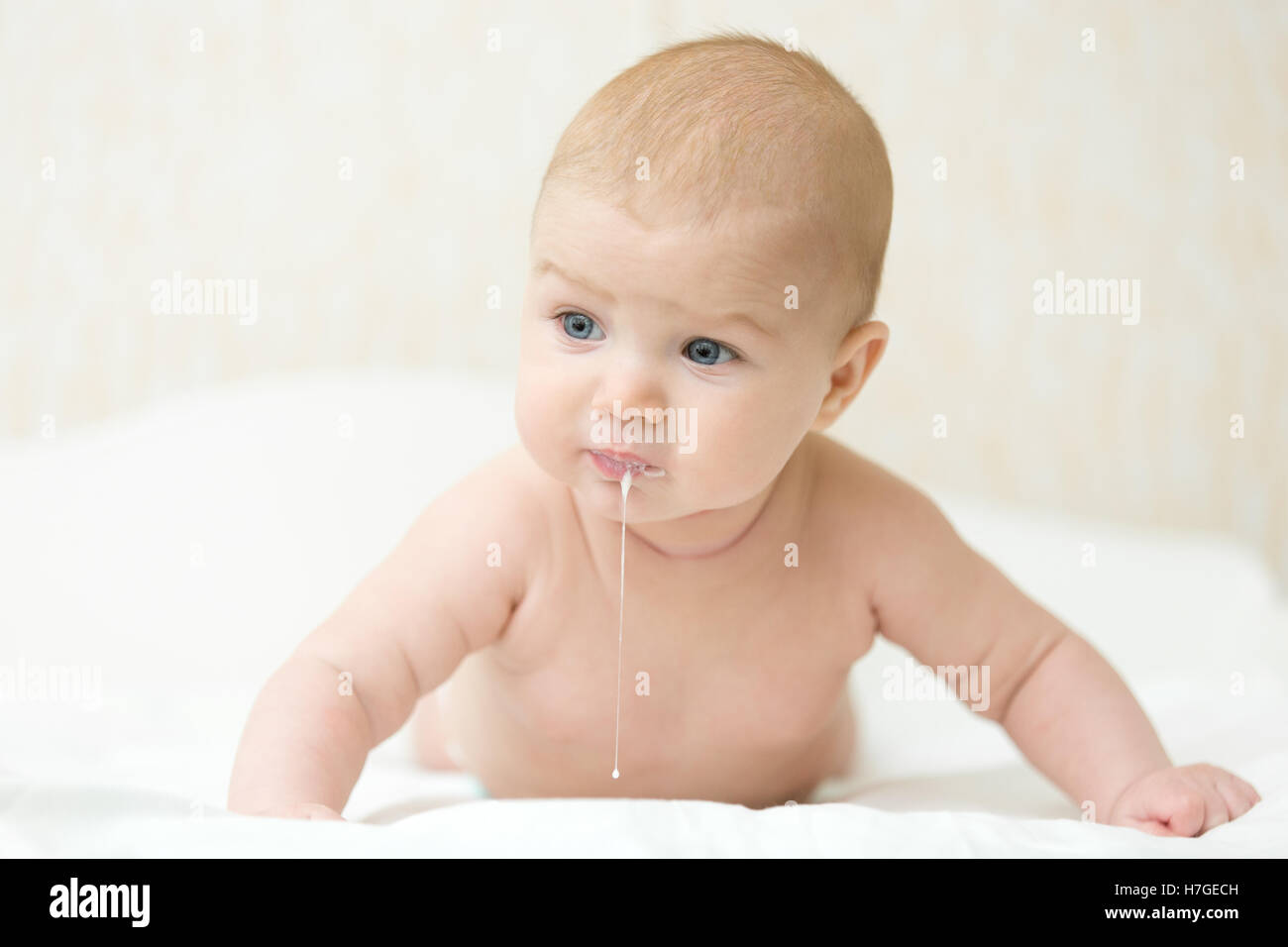 Cute baby raises head and chest, burping after eating Stock Photo - Alamy