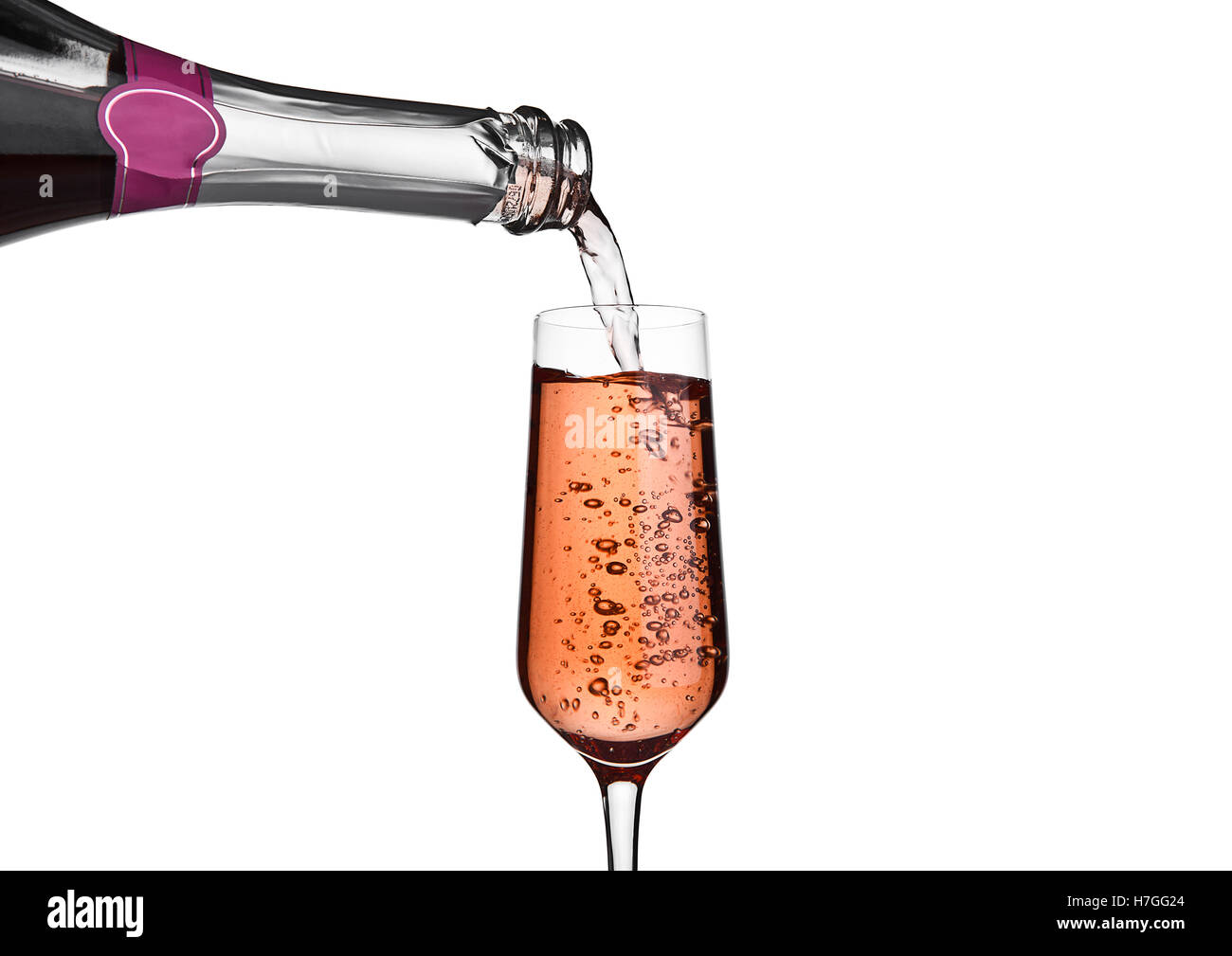 Pouring pink rose champagne from bottle to glass on white background ...