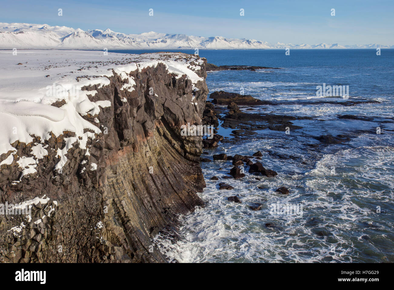 Basalt cliff in the snow in winter along the coast near Arnarstapi ...