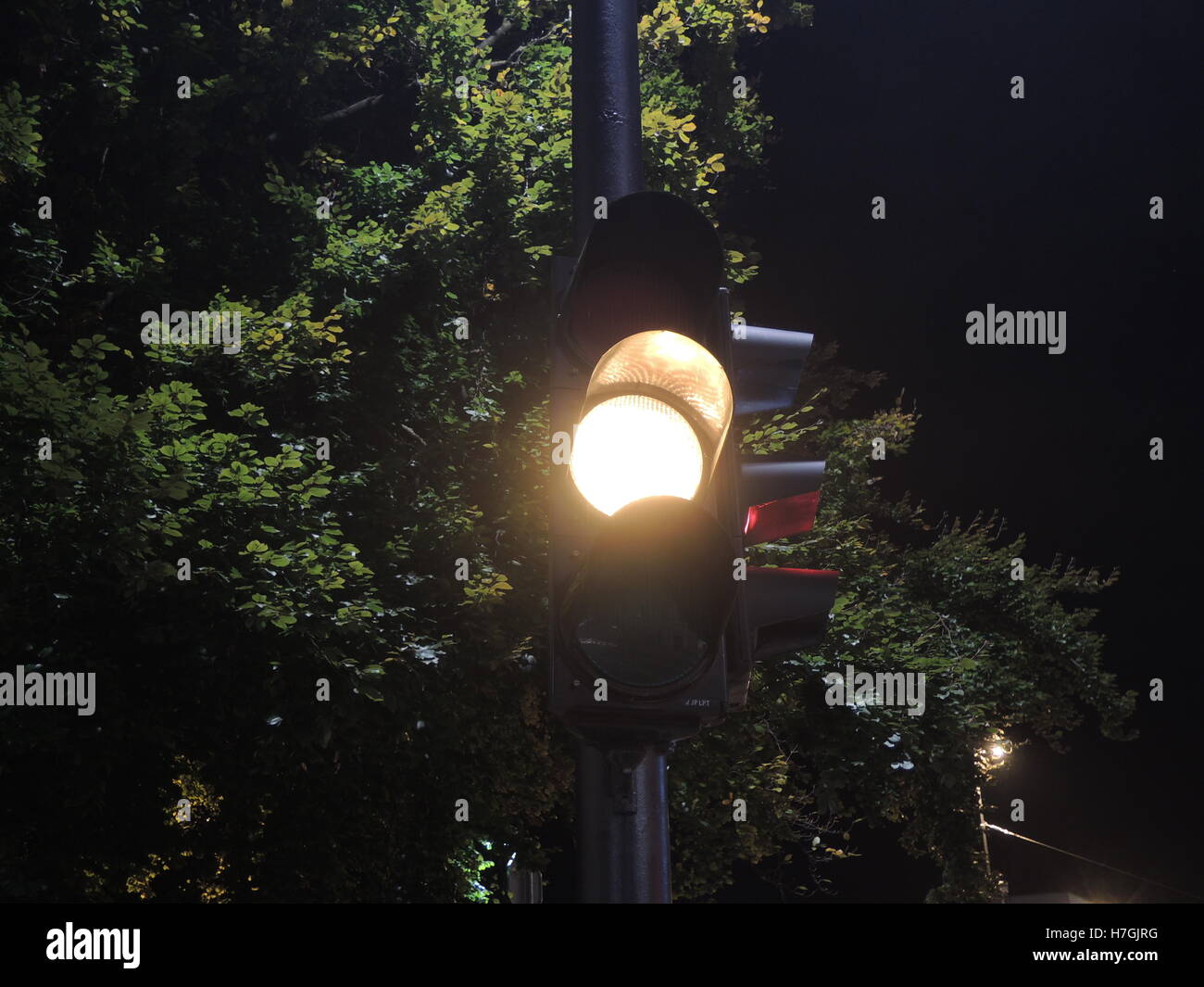 Traffic light at night-time showing yellow Stock Photo - Alamy