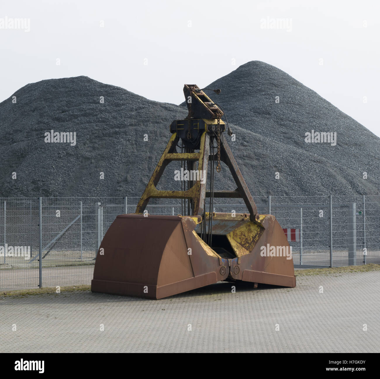 Huge crane grab and two piles of stones Stock Photo - Alamy