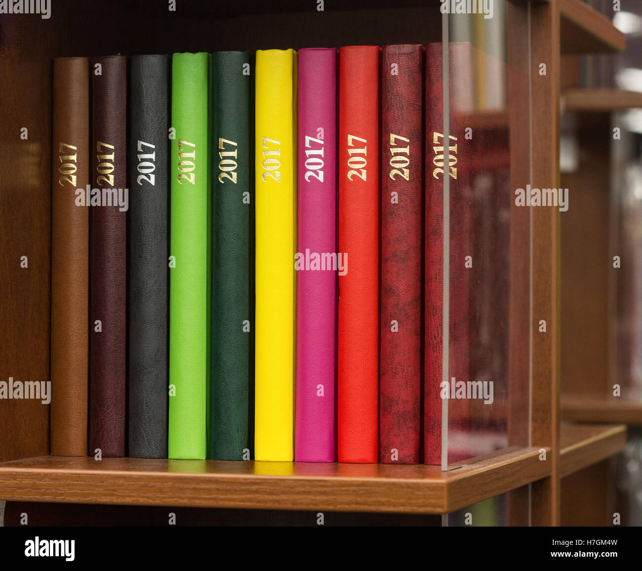 Color books with inscription 2017 on wooden shelf with glass partition ...