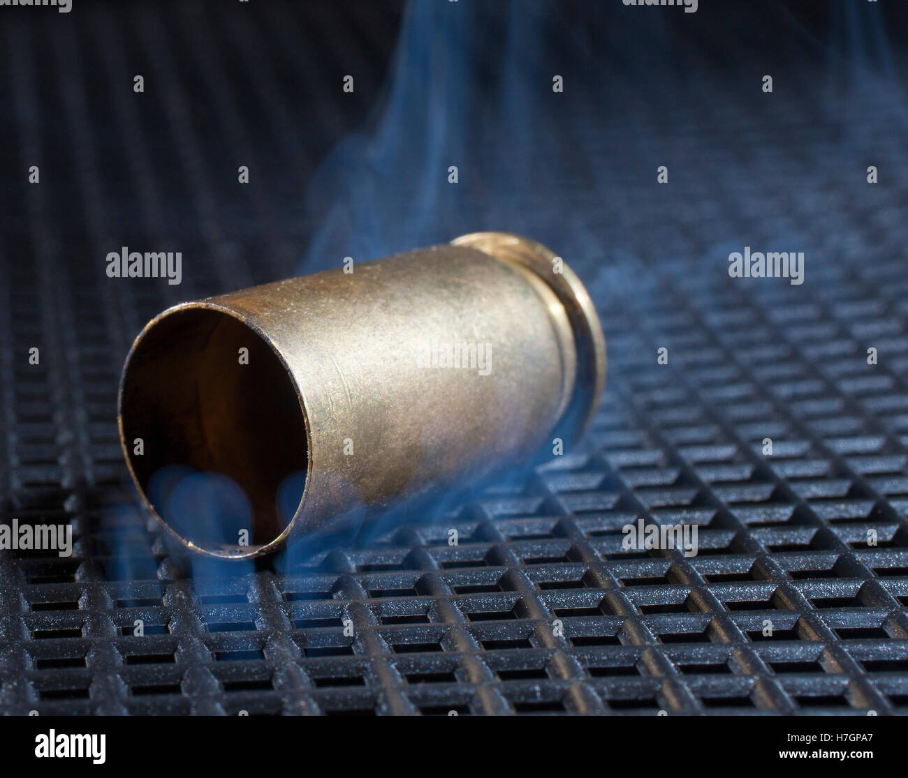 Empty brass casing from a handgun with smoke rising Stock Photo - Alamy