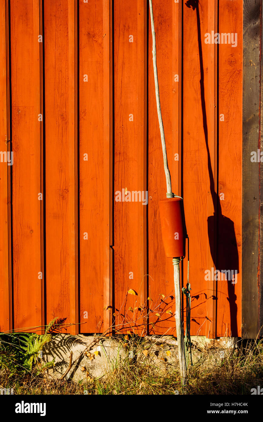 Handmade red fishing net marker leaning against a red wooden wall. Copy ...