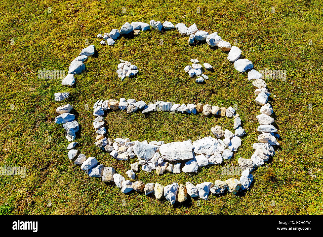smiling face icon made of pebble stones on mountain meadow Stock Photo ...