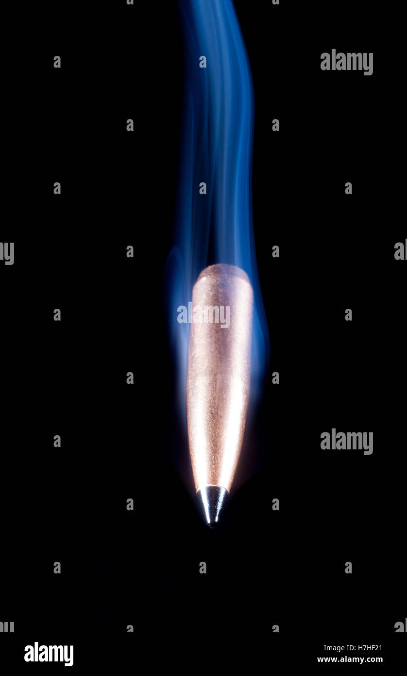 Bronze colored bullet with smoke behind on a black background Stock ...