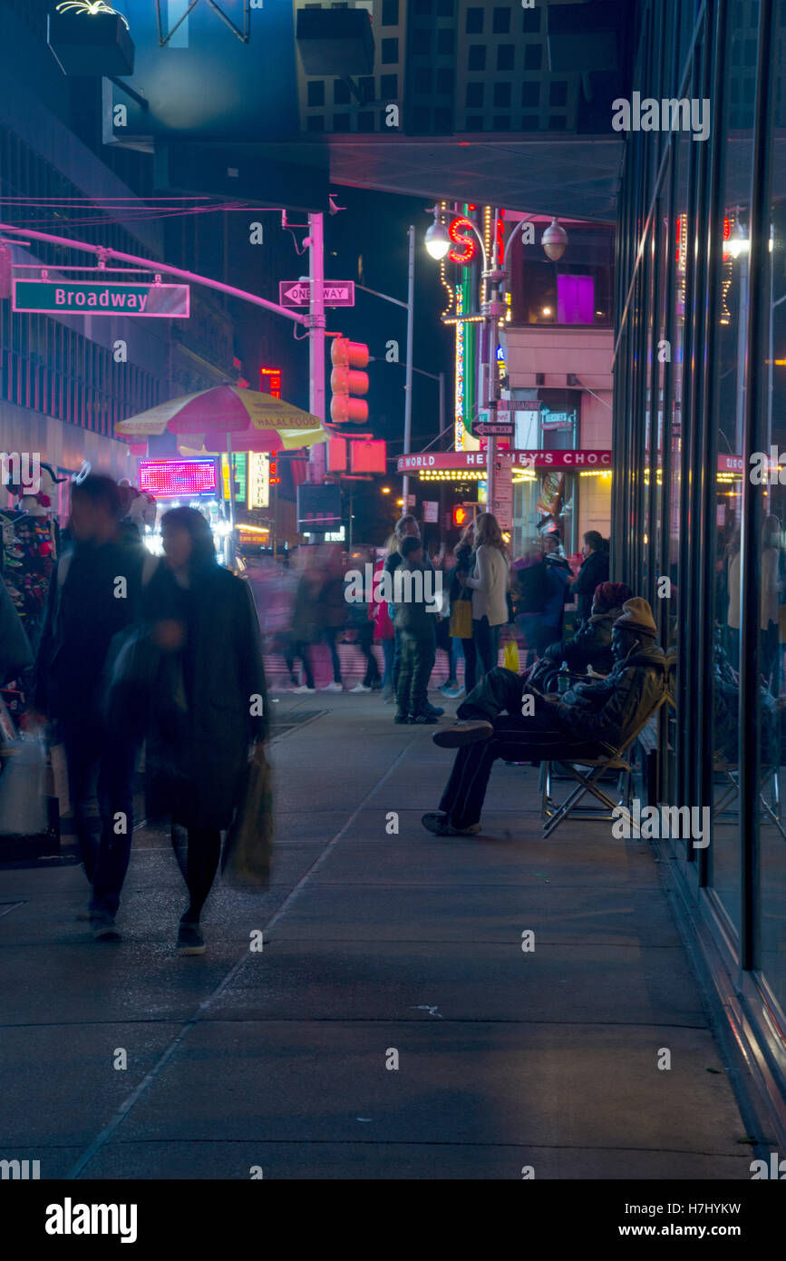 Night in Times Square, New York City. Sidewalk traders lit by nearby ...