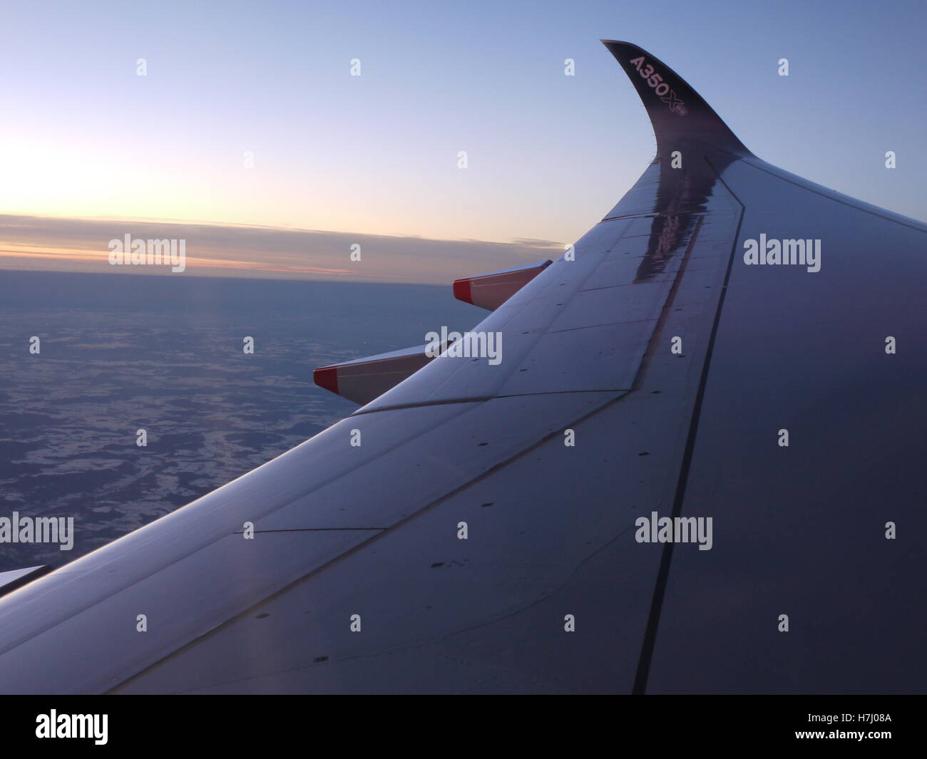 A wing of an Airbus A 350 airplane during flight above France at sunset ...