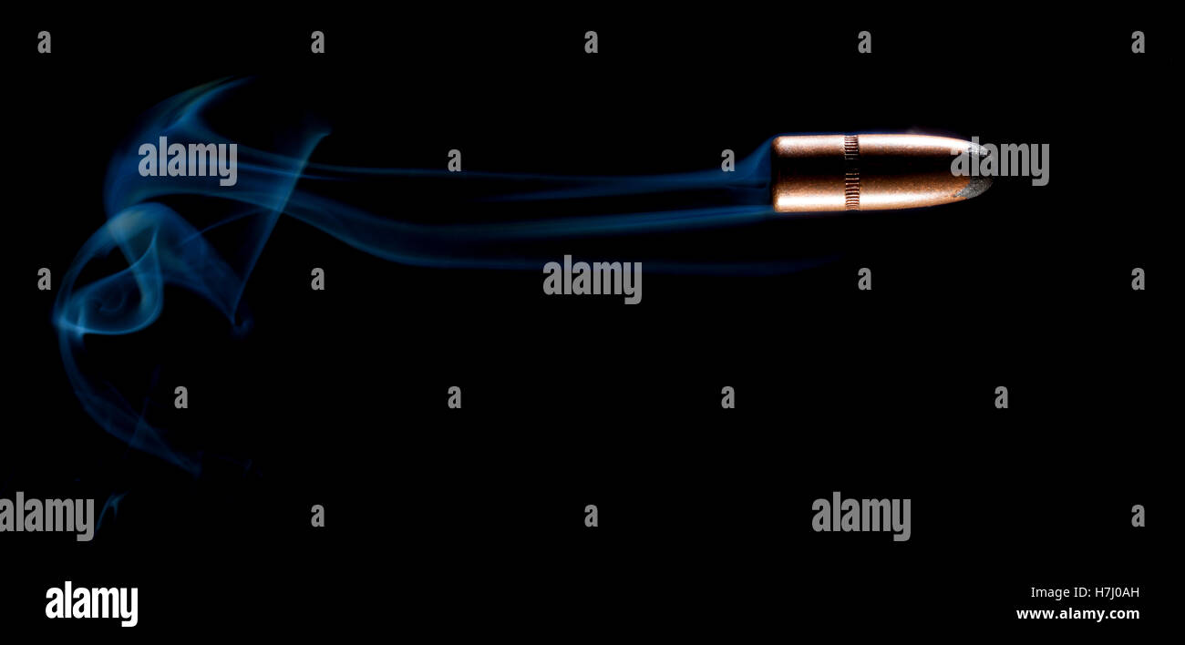 Copper plated bullet with smoke on black moving on the top of the frame ...