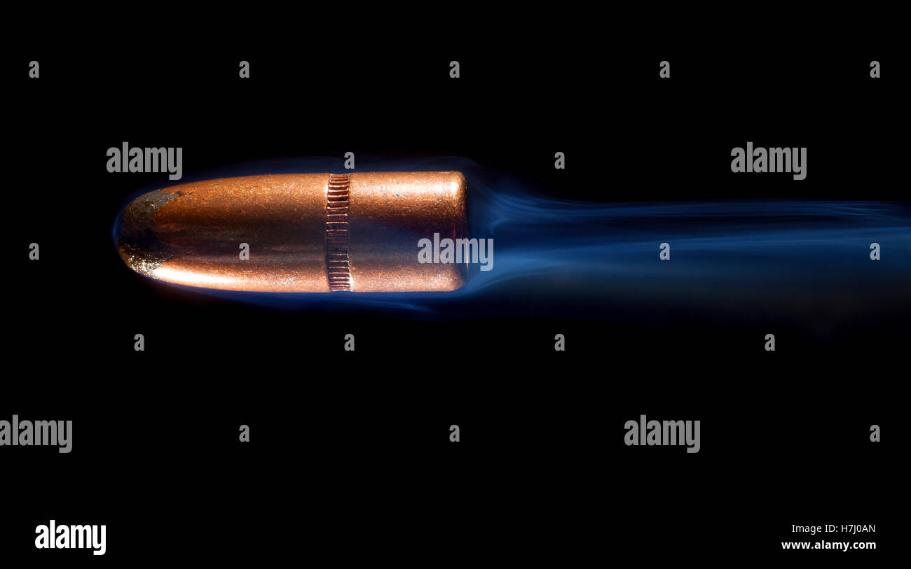 Lead bullet with a copper coating on black with smoke behind Stock ...