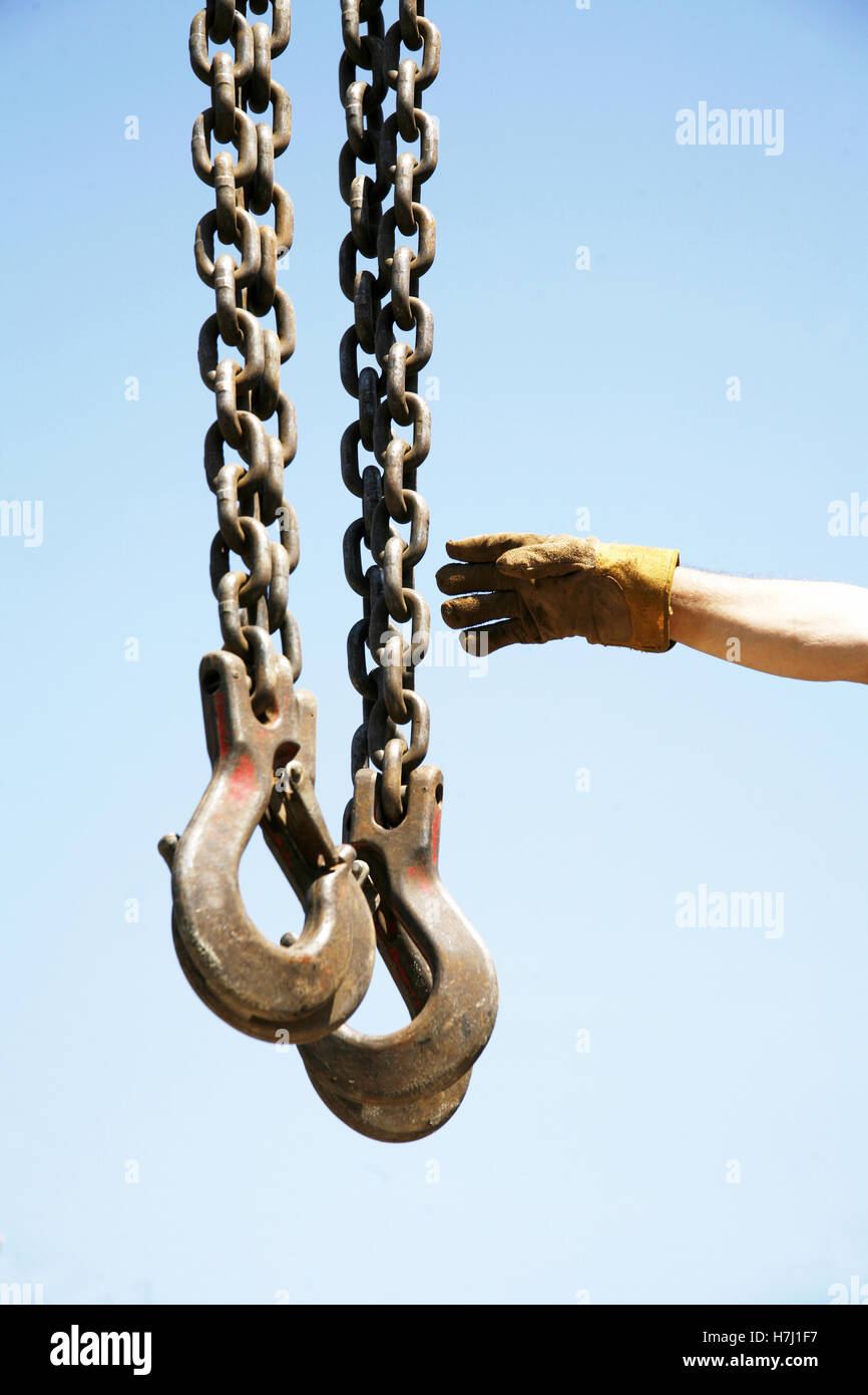 Long rusty chains with crane hook as industrial background. Hand of ...
