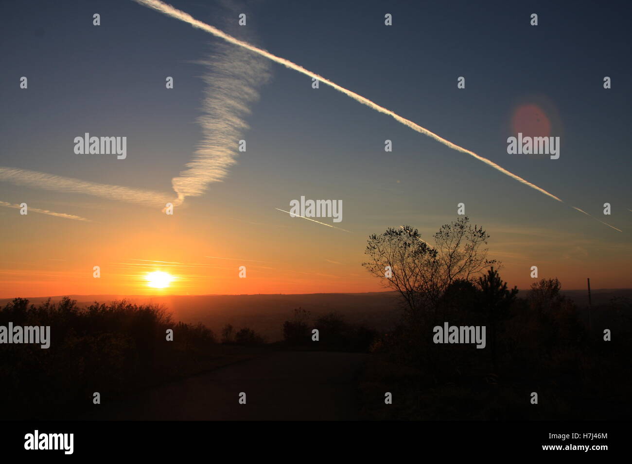 Clouds and jet contrails over the sunset with trees Stock Photo - Alamy