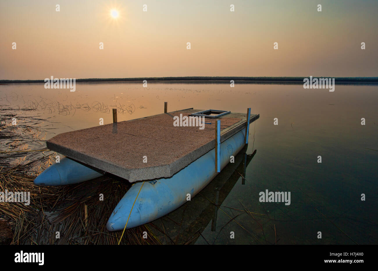 Lake in Canada at sunrise with a pontoon boat on shore Stock Photo - Alamy