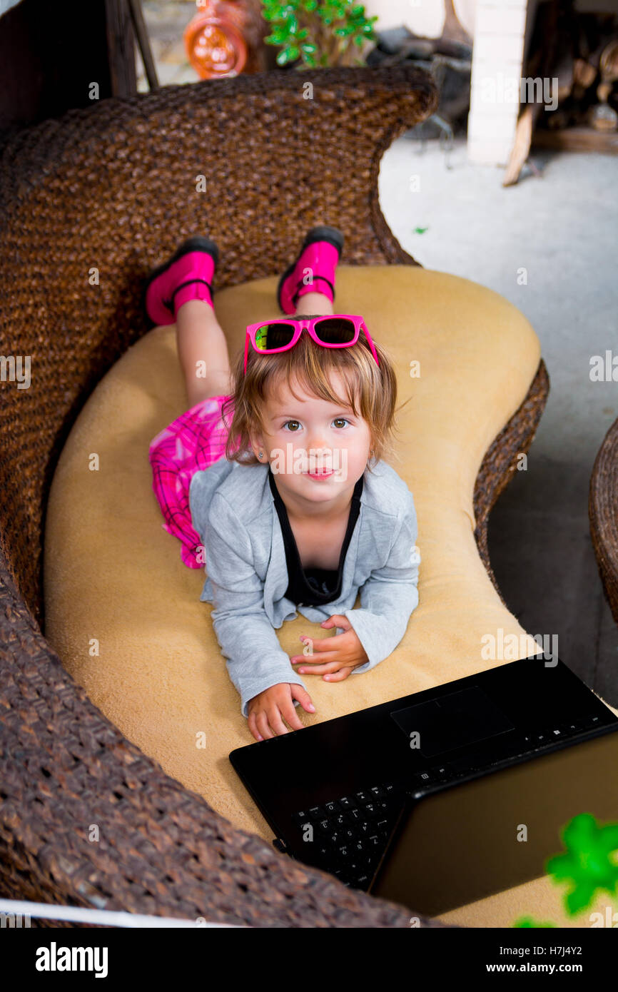 Little girl using laptop. Child in pink skirt and pink boots, pink ...