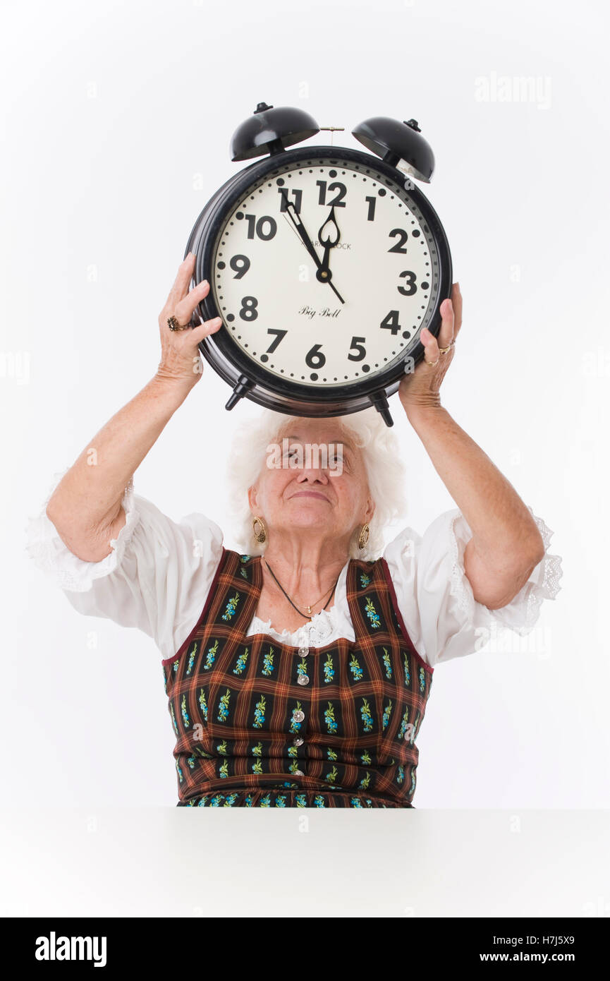 It's almost high noon, elderly woman holding an alarm clock over her ...