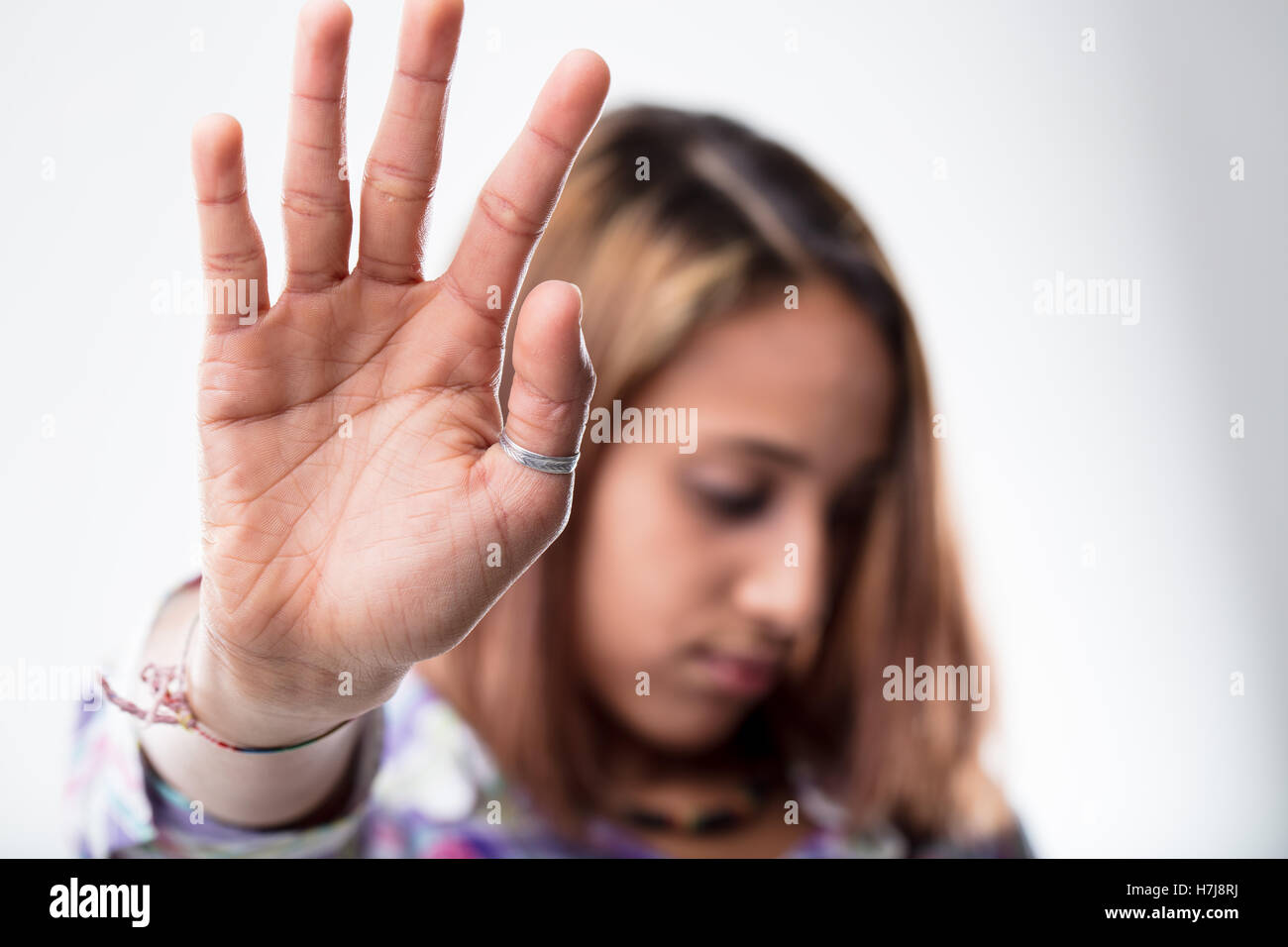 Young woman making a dismissive hand gesture raising her palm to call a ...