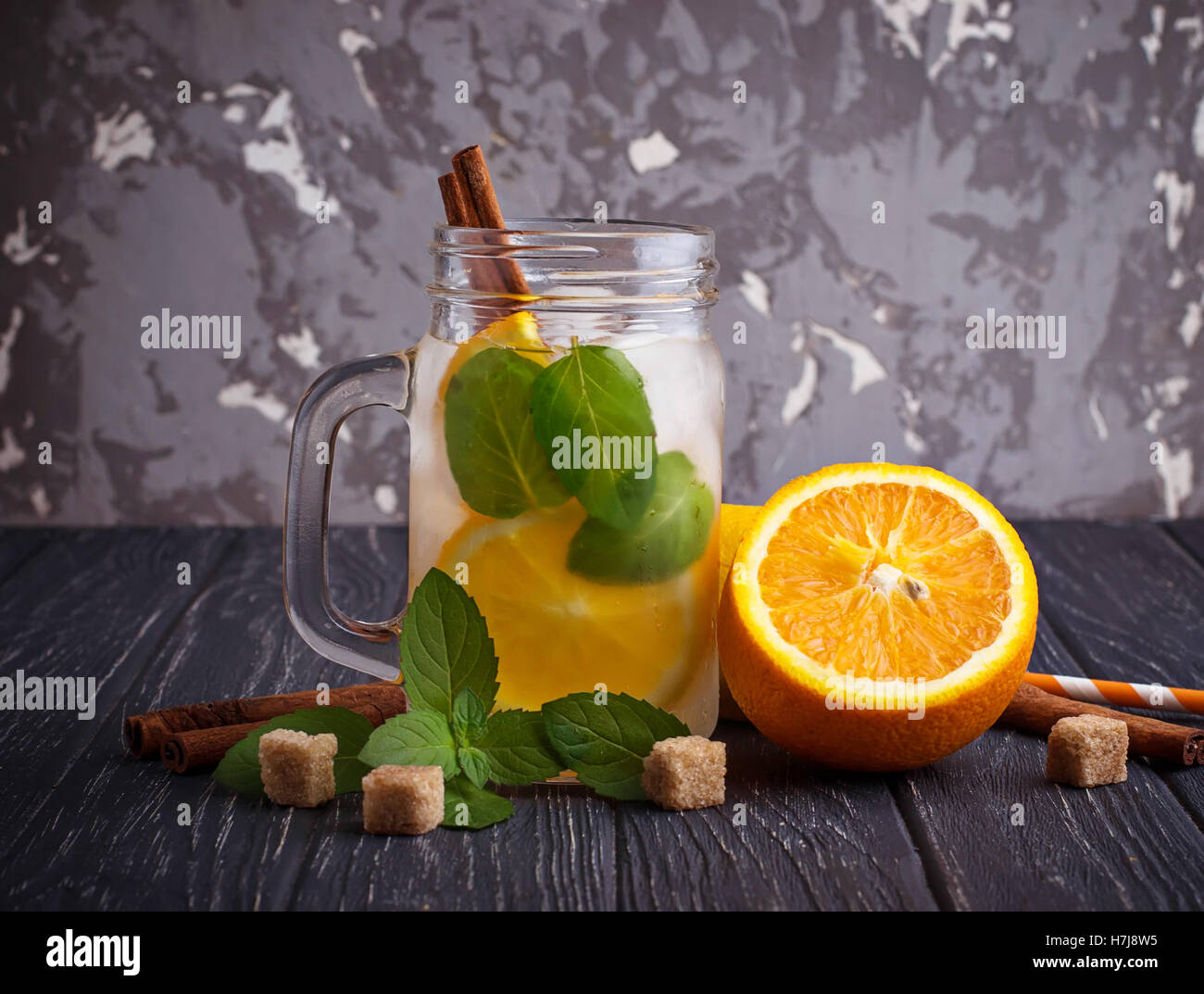 Detox water with orange, mint and cinnamon in jar. Selective focus ...