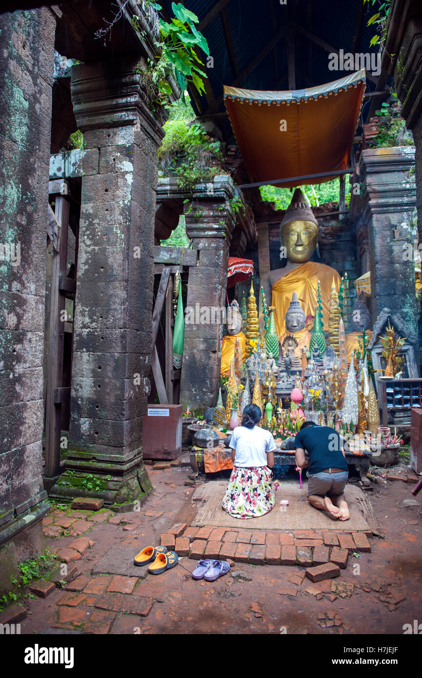 Buddhist devotees pray to Wat Phu, a ruined Khmer Hindu temple complex ...