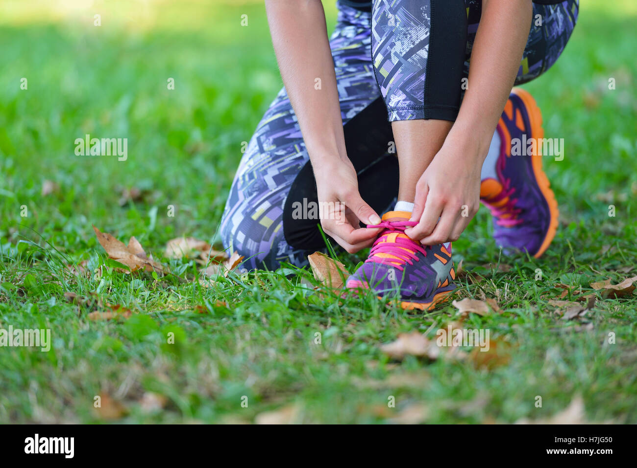 Female jogger tying laces on her shoes outside Stock Photo - Alamy