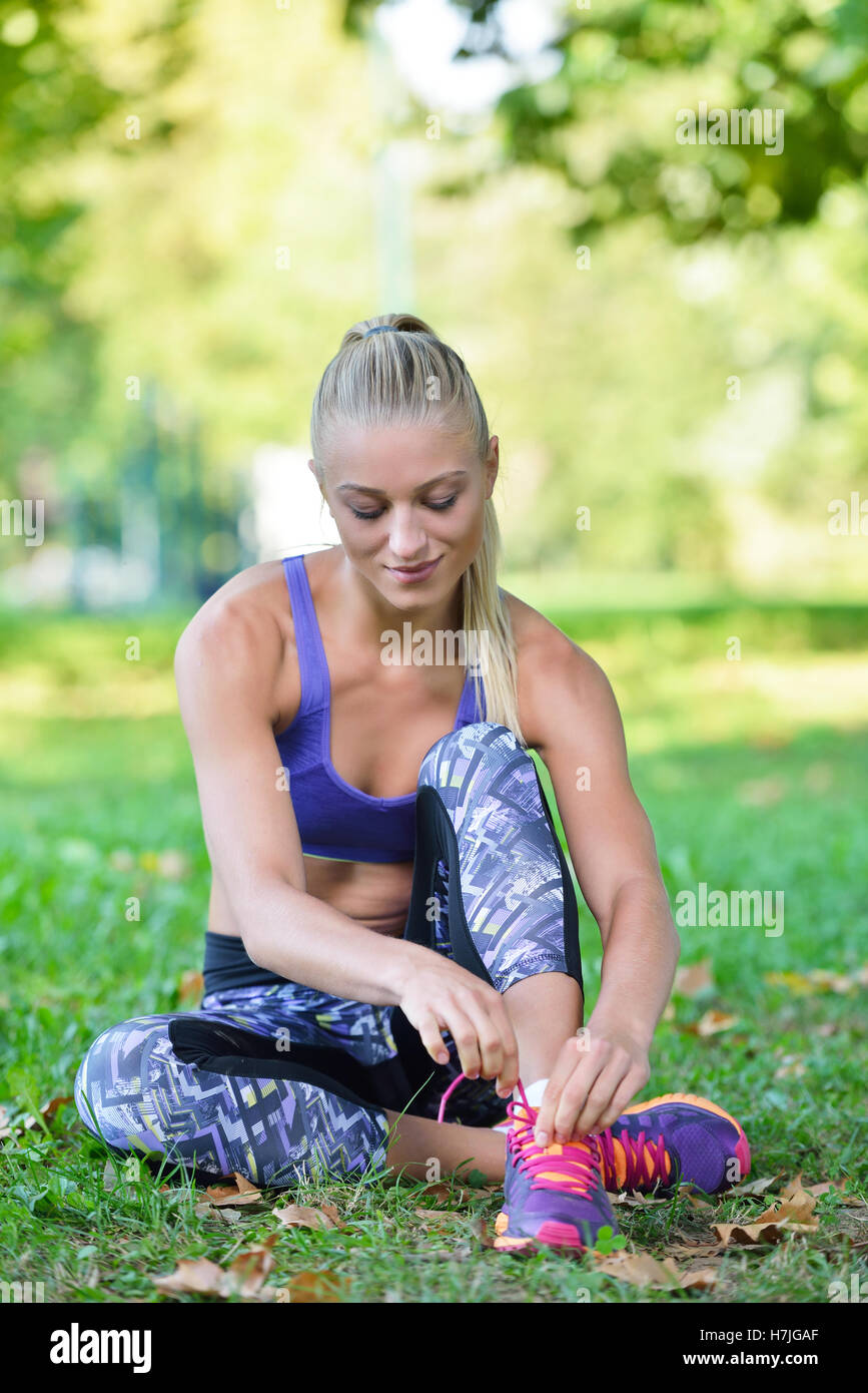 Female jogger tying laces on her shoes outside Stock Photo - Alamy