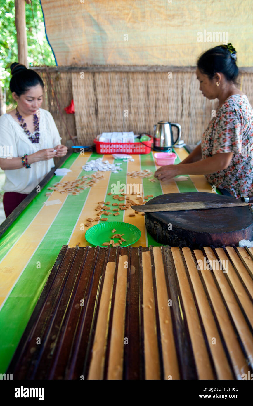 Woman cut and wrap coconut candy at a coconut factory outside of Ben ...
