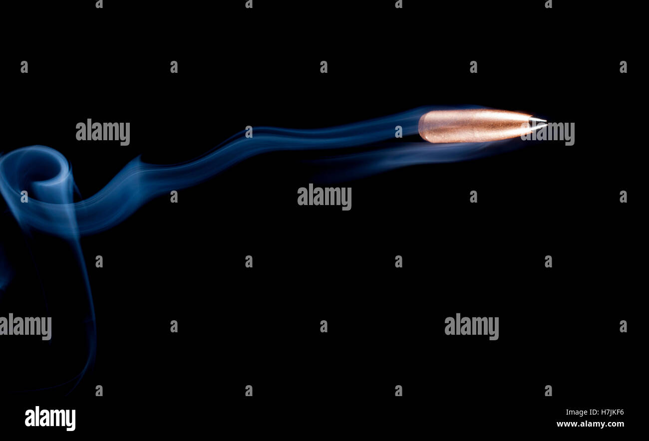 Copper plated lead bullet on black with a polymer tip and smoke behind ...