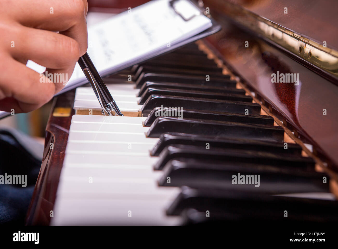 Man playing piano tune with ballpen pen in right hand from notes Stock ...