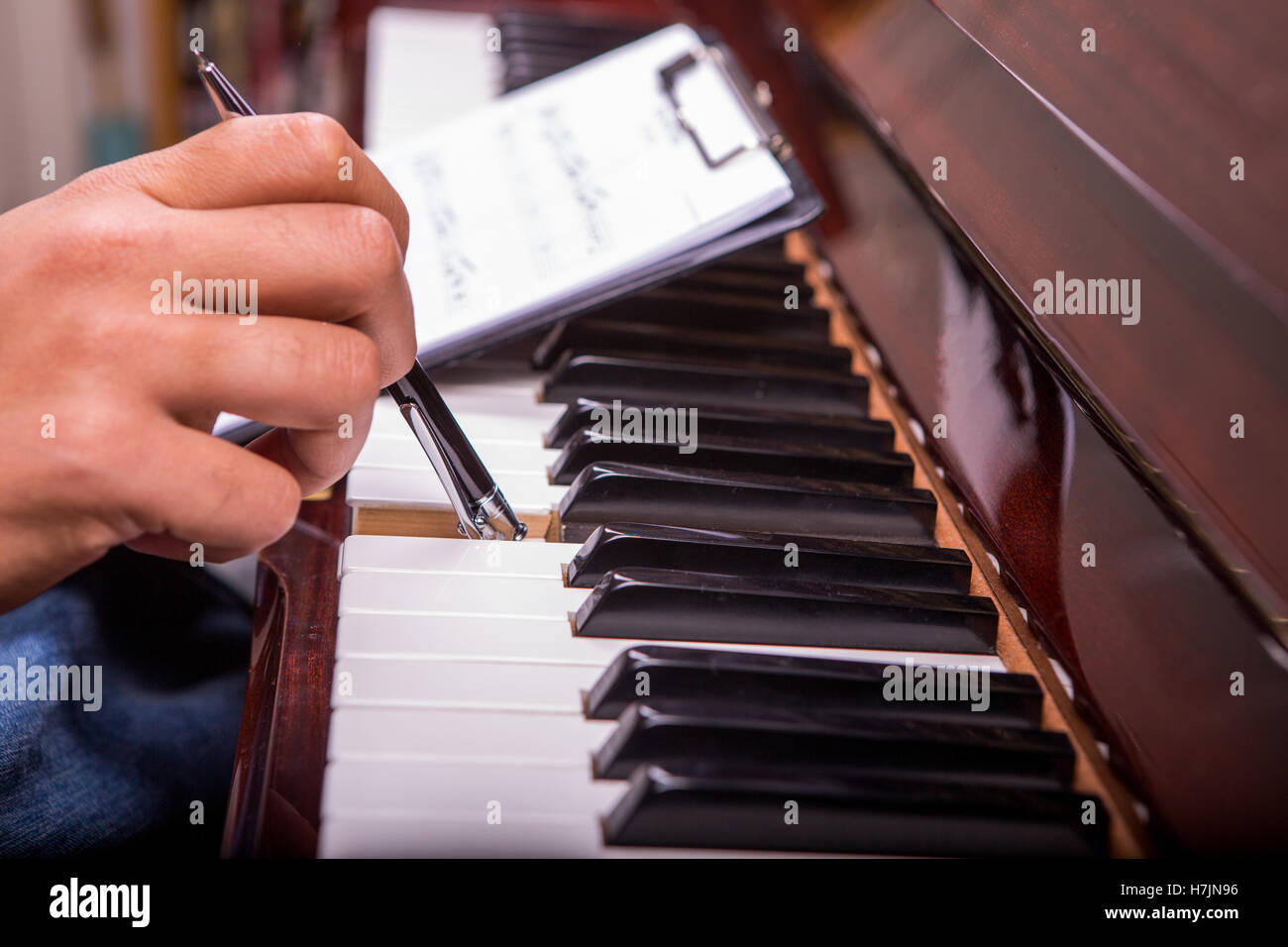 Man playing piano with ballpen in right hand and holding notes in left ...