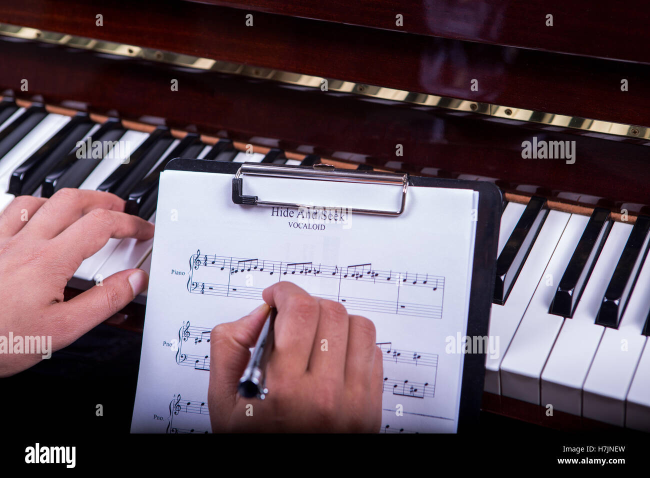 Man playing piano and taking nodes writing with right hand ballpen and ...