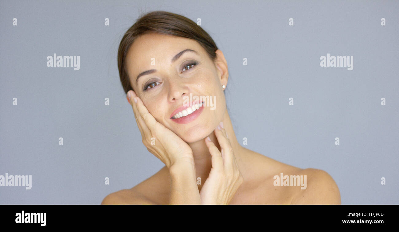 Happy young woman with hands on cheek Stock Photo - Alamy