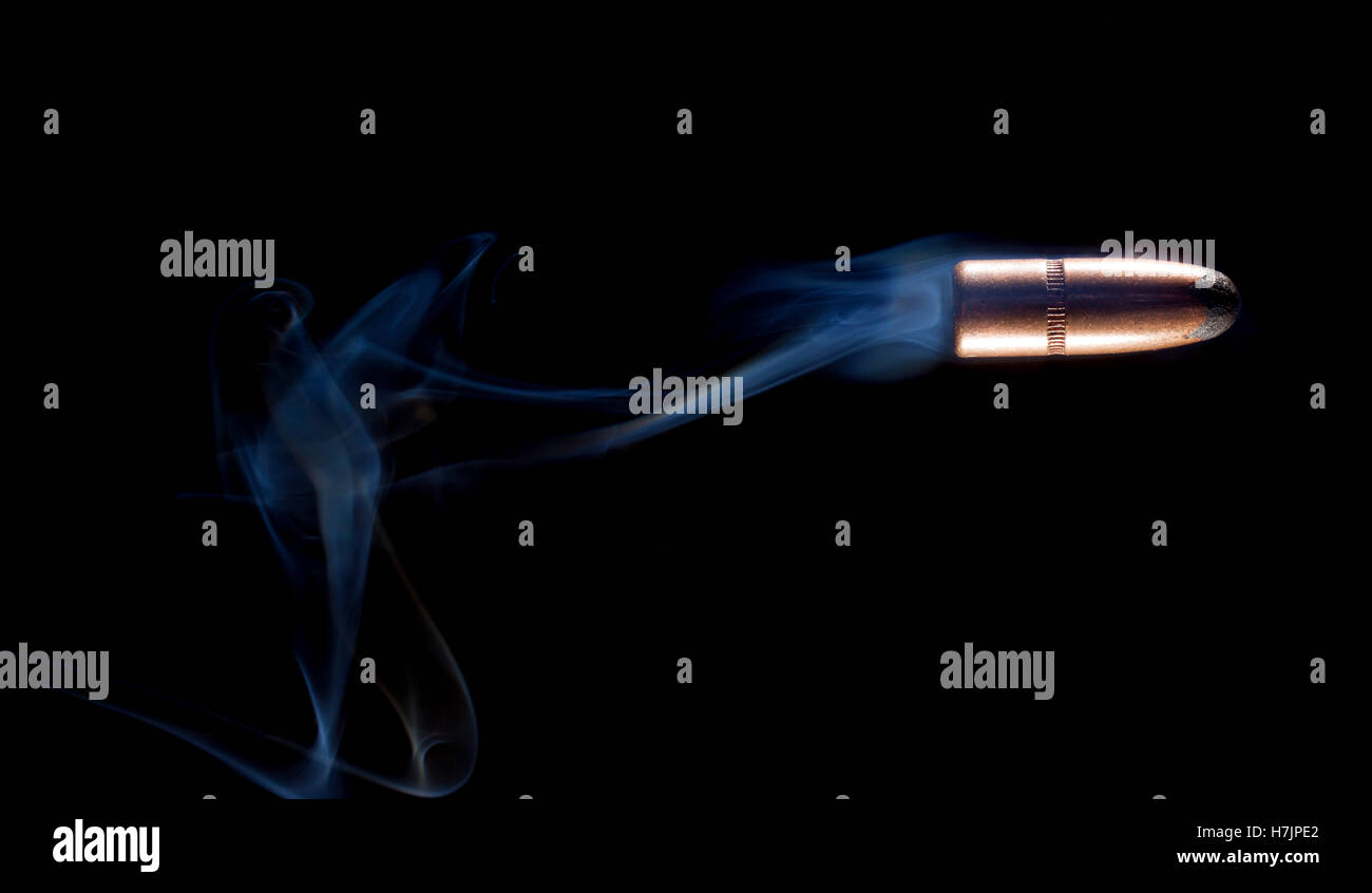 Smoke swirling behind a copper plated lead bullet on a black background ...