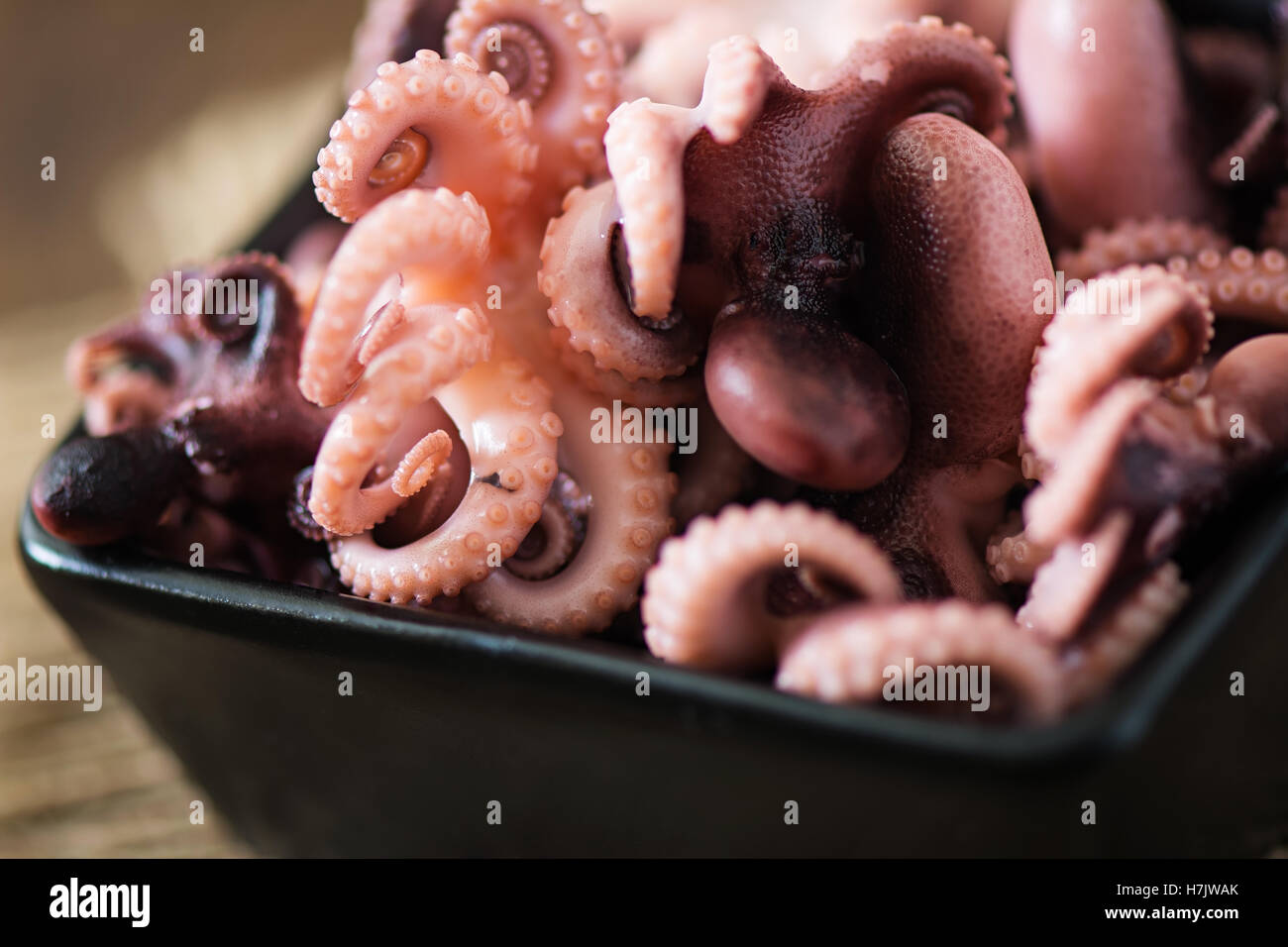Boiled small octopus on a black plate Stock Photo - Alamy