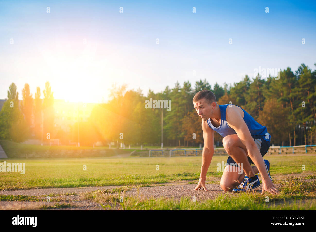 Man in low start position on old stadium. Athlete in starting position ...