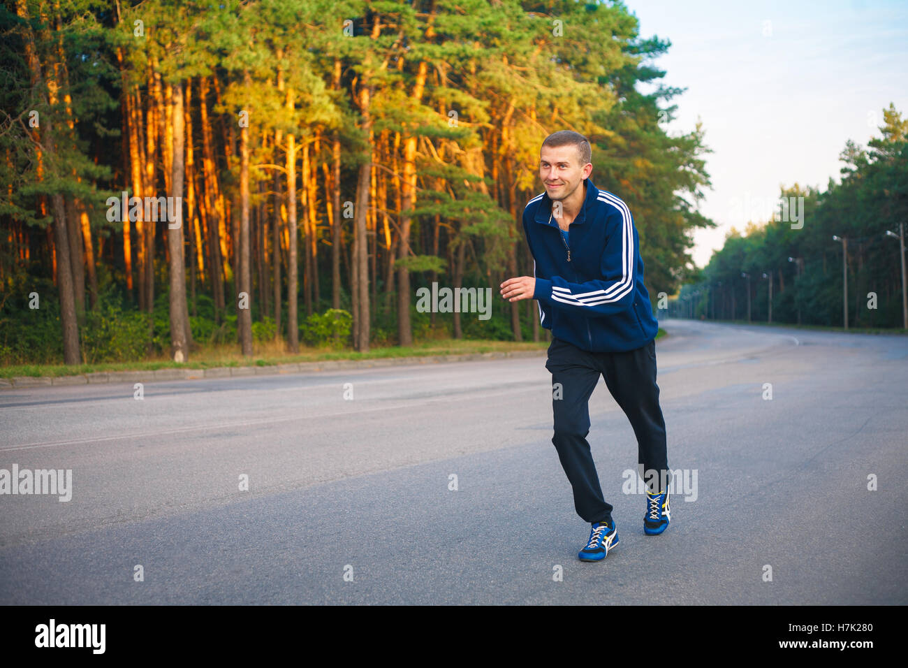 Young handsome sportsman running outdoors. Fit sporty man on road Stock ...