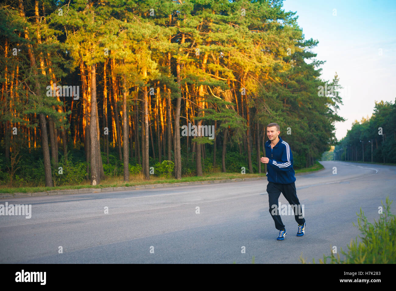 Young handsome sportsman running outdoors. Fit sporty man on road Stock ...
