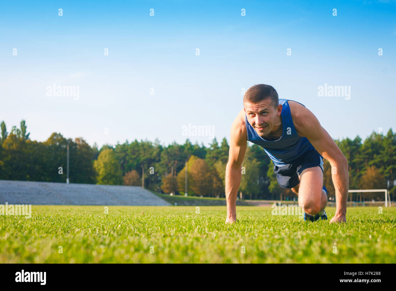 Man in low start position on old stadium. Athlete in starting position ...
