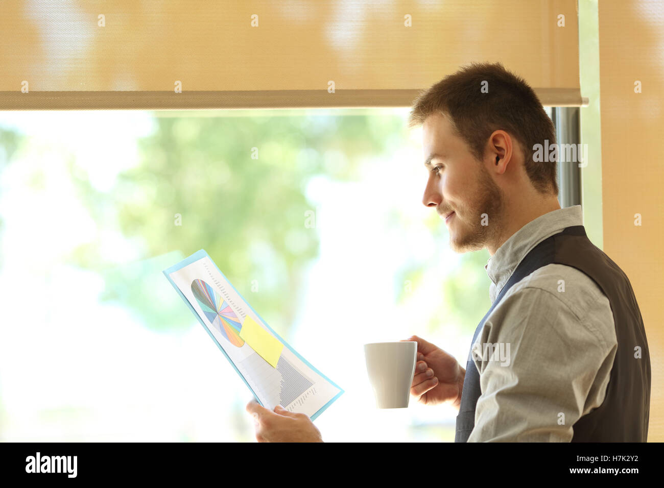Side view of a business man reading growth statistics and drinking ...