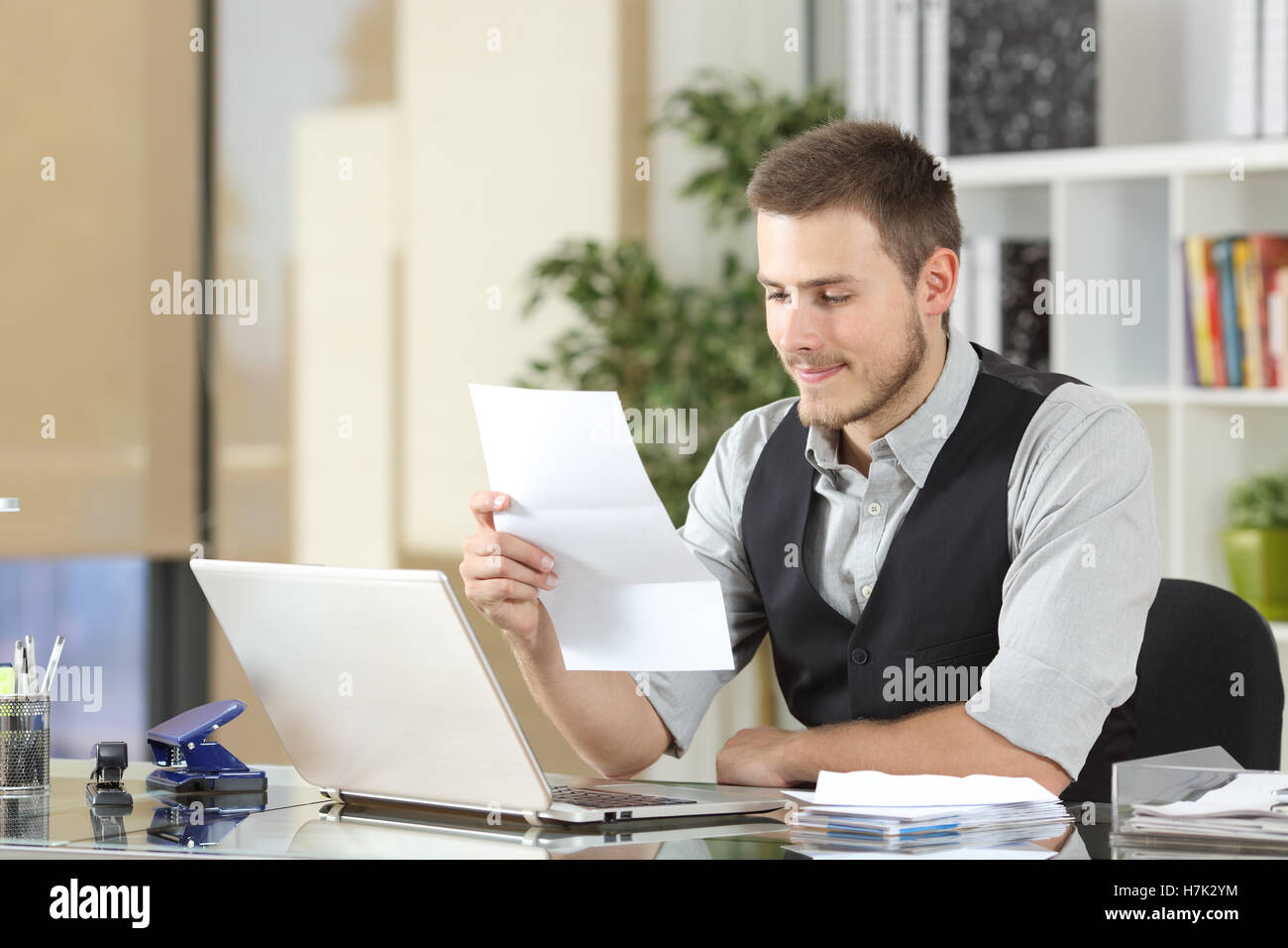 Happy businessman reading a letter sitting in a desk at office Stock ...