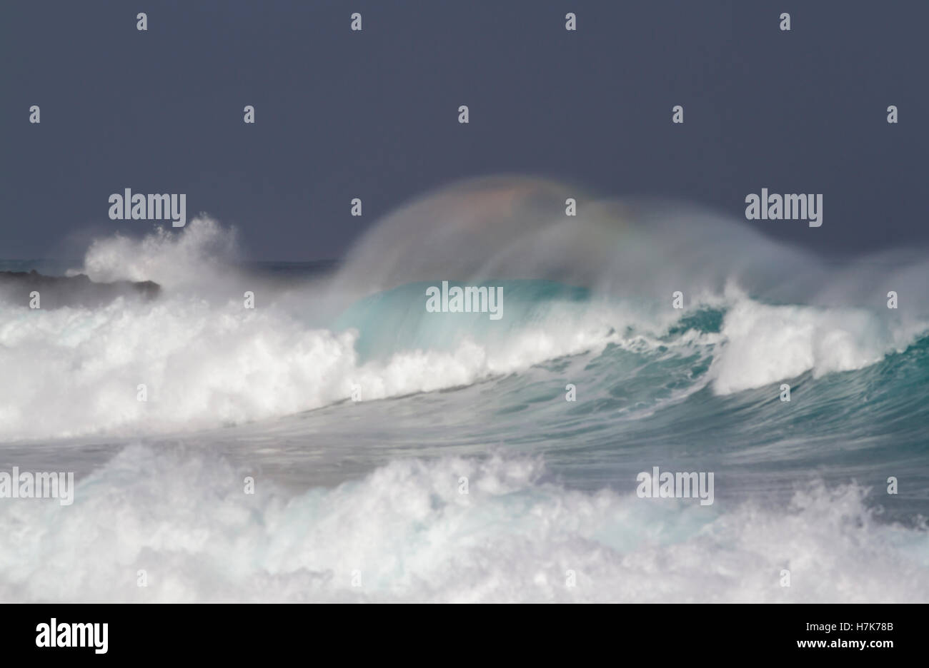 Rainbow colors light up the spray of a beautiful Ocean wave on the ...