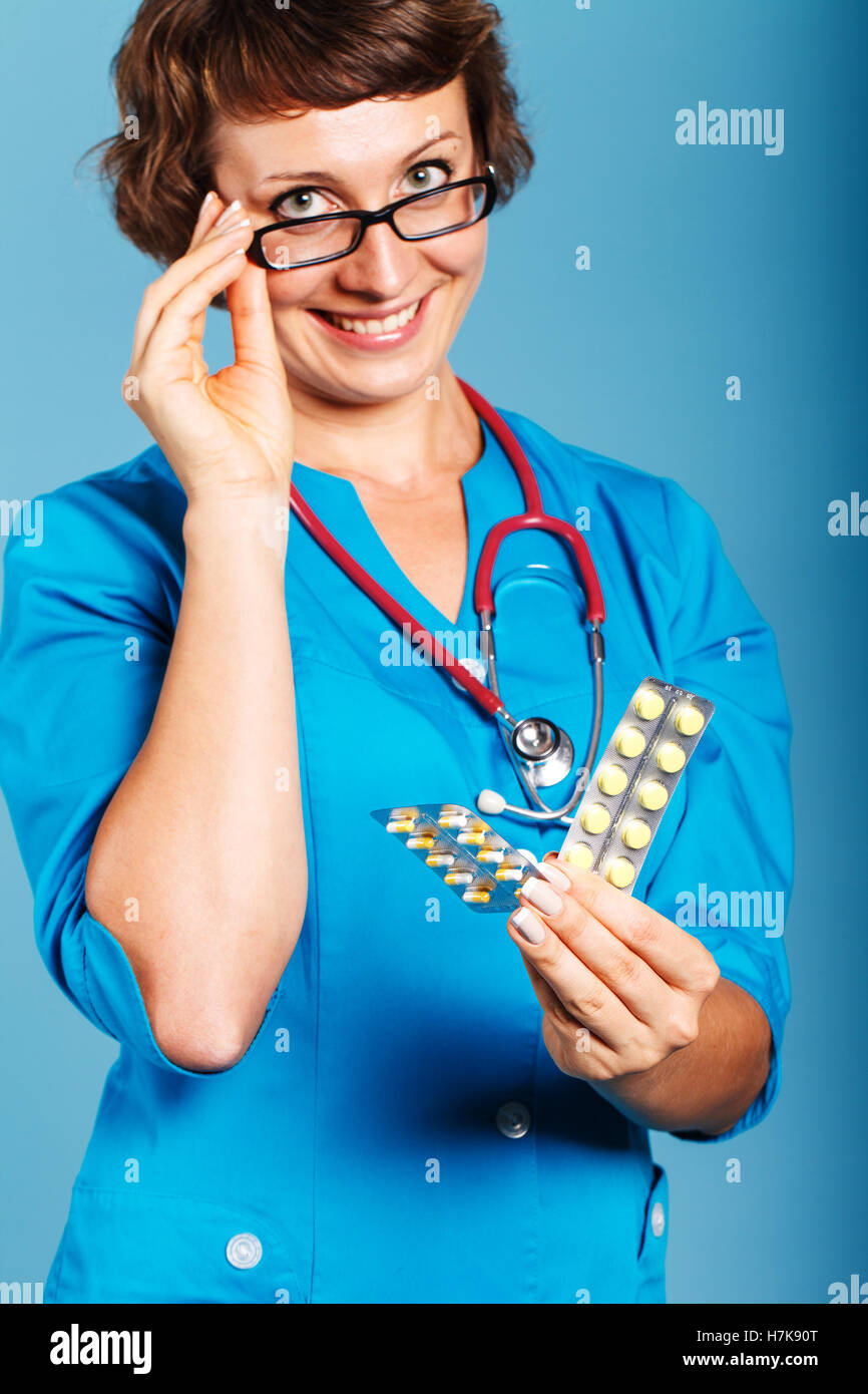 Doctor with pills in hand close-up in the studio on a blue background ...