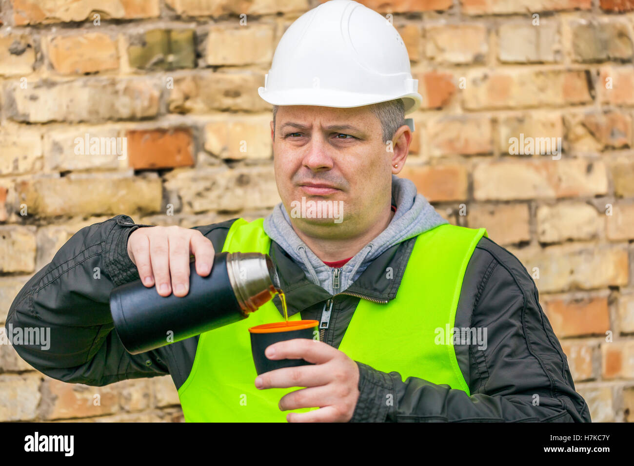 Construction Engineer drinking tea near stone wall Stock Photo - Alamy