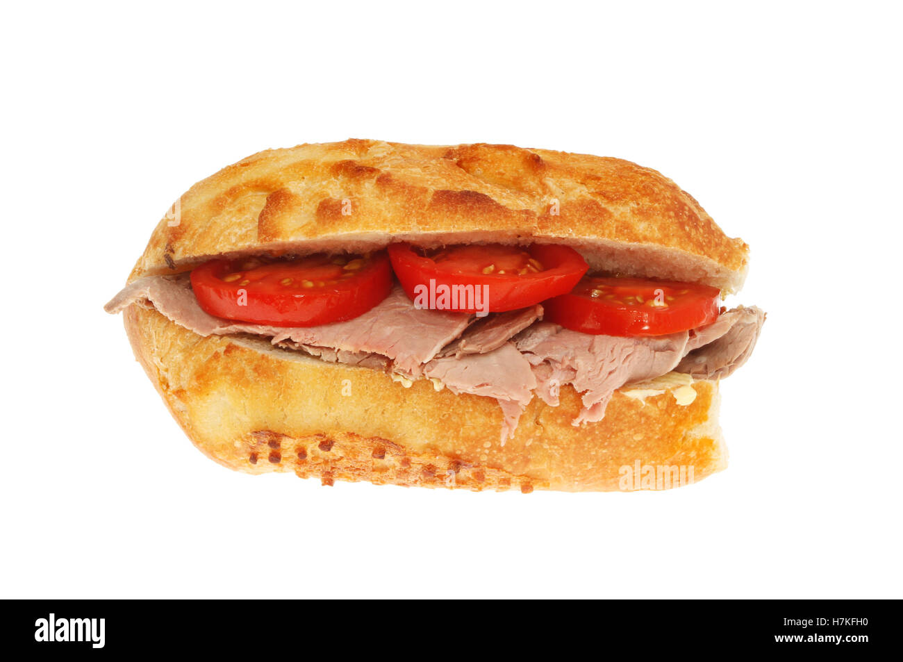 Beef and tomato in a crusty giraffe bread roll isolated against white ...