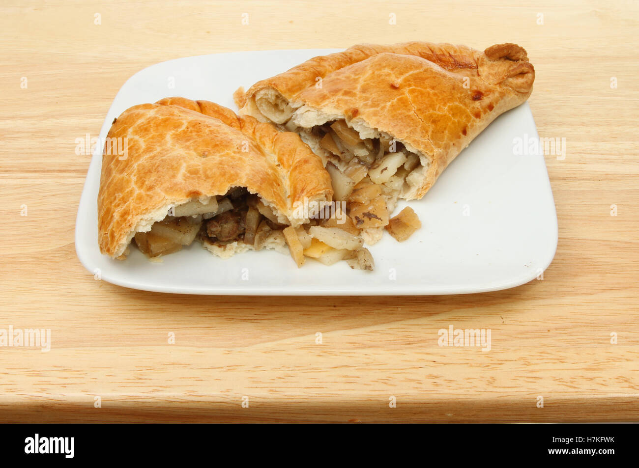 Broken Cornish pasty on a plate on a wooden tabletop Stock Photo - Alamy