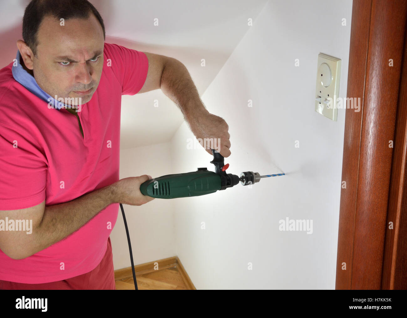 Man with angry face drilling a wall with electric drill Stock Photo - Alamy