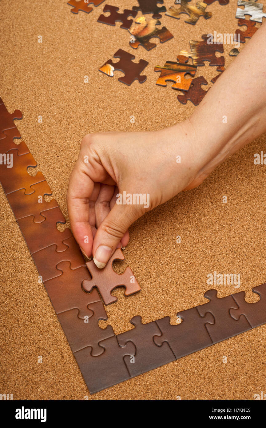 hand playing a piece and solving a jigsaw puzzle Stock Photo - Alamy