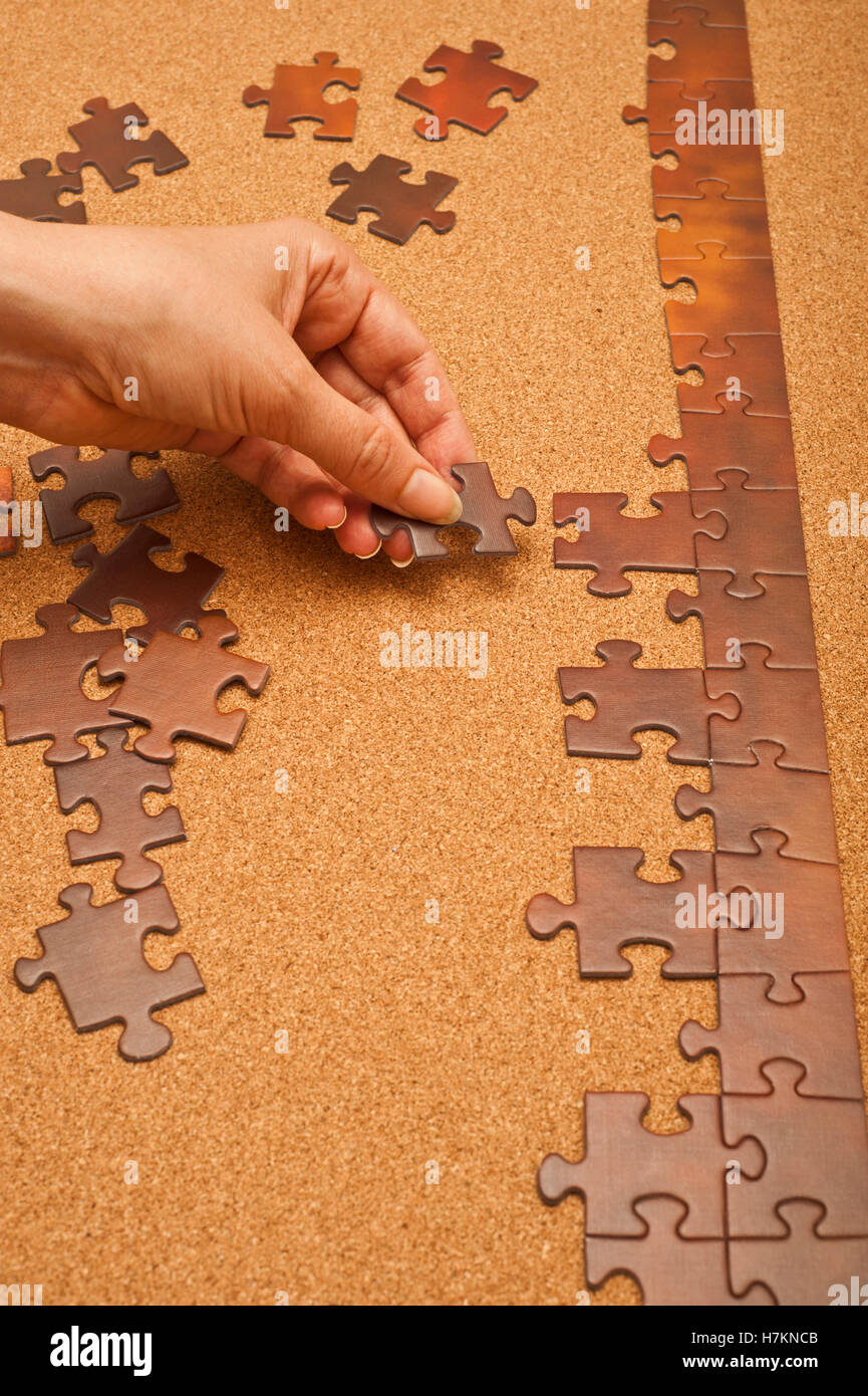 hand playing a piece and solving a jigsaw puzzle Stock Photo - Alamy