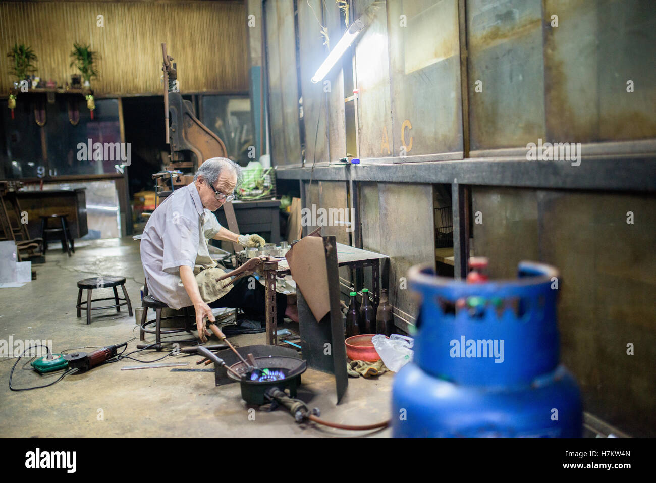 An old man soldering some stuff in a Bangkok shop Stock Photo - Alamy