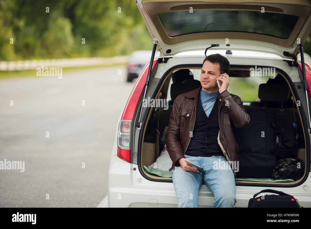 Calling friends. Happy young man talking mobile phone and sitting on a ...