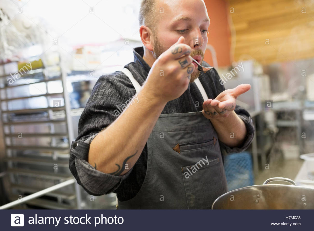 Chef tasting sauce over pot in restaurant commercial kitchen Stock ...
